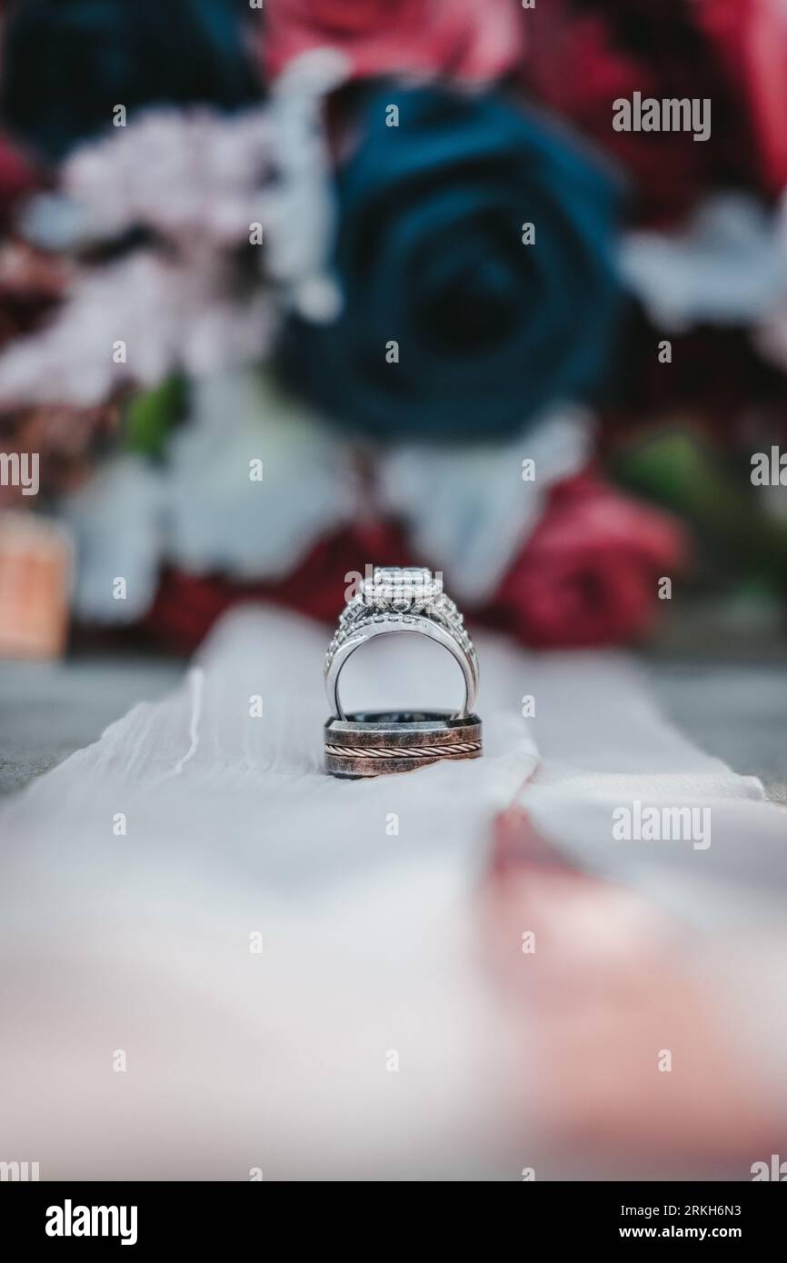 A vertical closeup of wedding rings near rose flowers Stock Photo - Alamy
