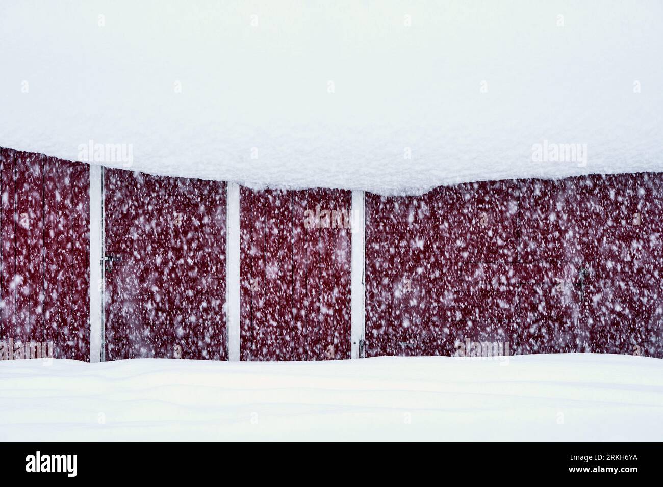 A winter scene with snow covering a rooftop and falling to the ground ...