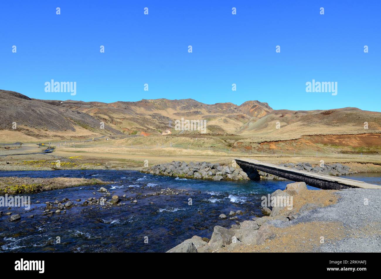 Wooden platform bridge extending over a river in scenic rural Iceland ...