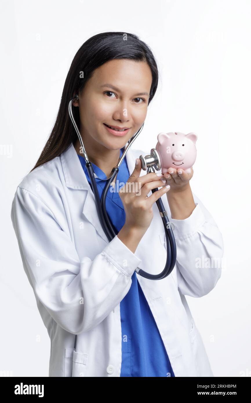 Asian American Woman Doctor examining a piggy bank, concept show the ...