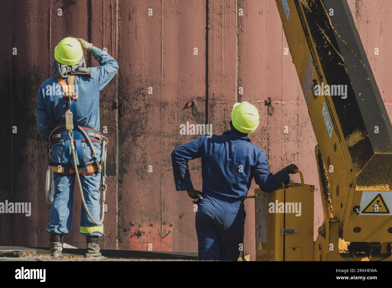 Rear view of two construction workers working at construction site hi ...