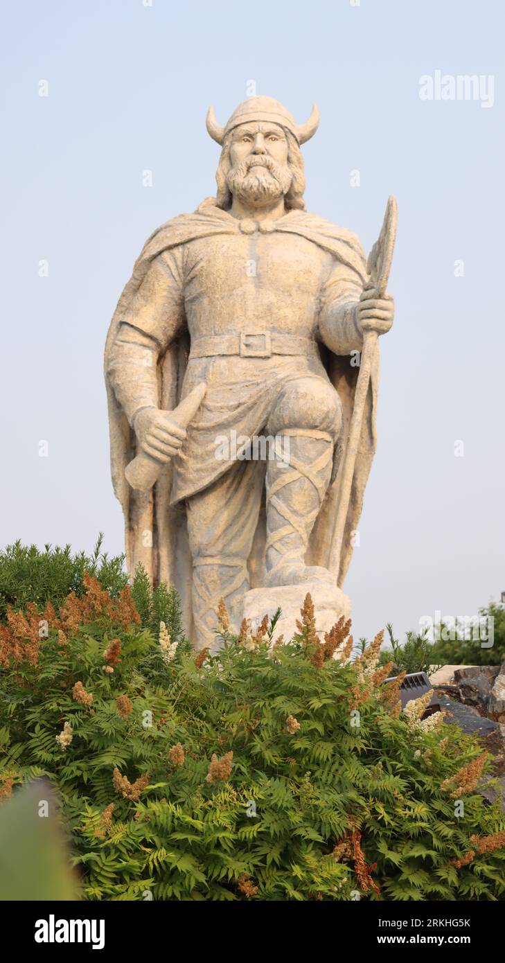 An eige Stone Viking statue is pictured on a hill with lush green ...