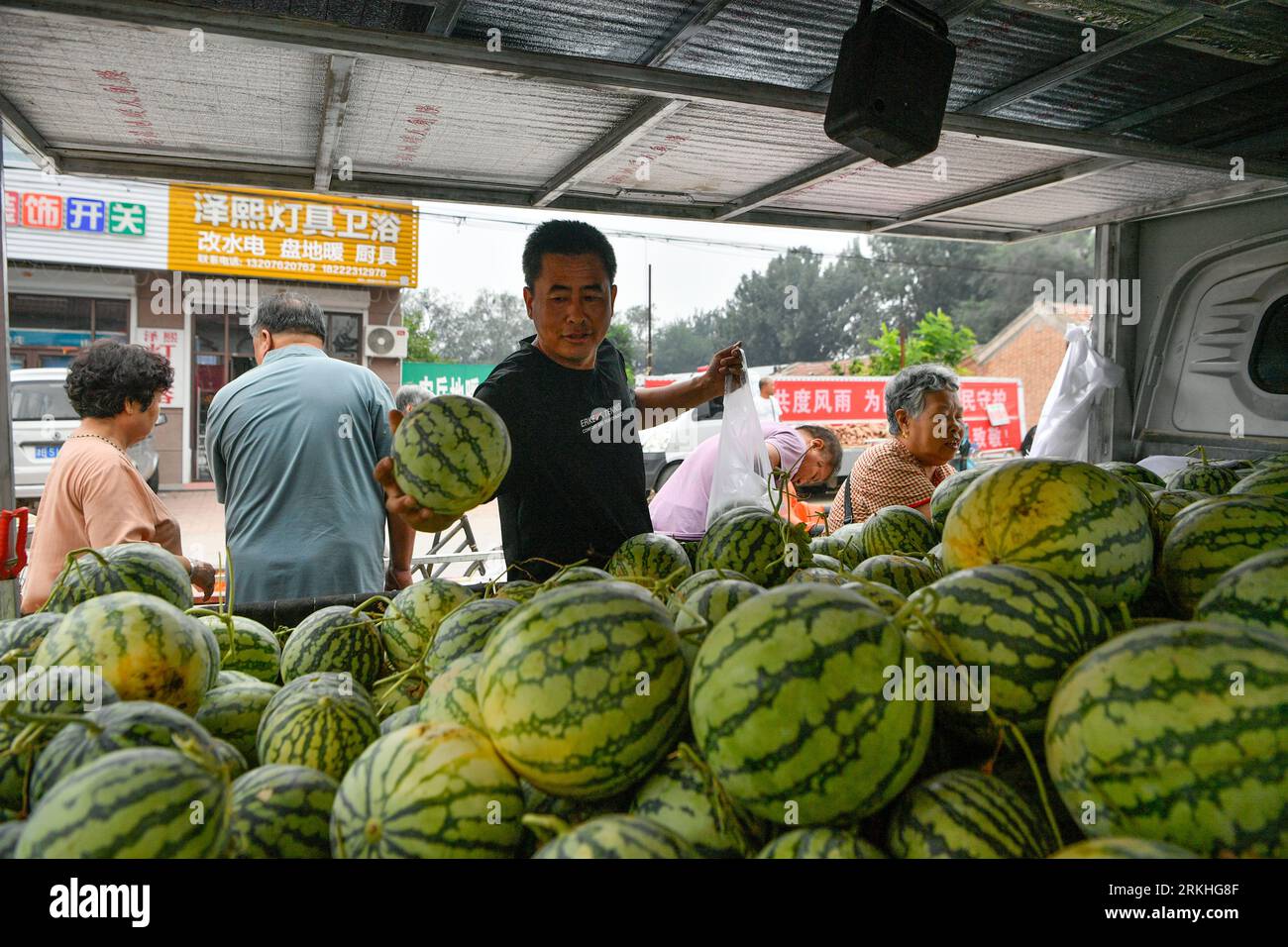 Tianjin. 25th Aug, 2023. A vendor picks out watermelons for villagers ...