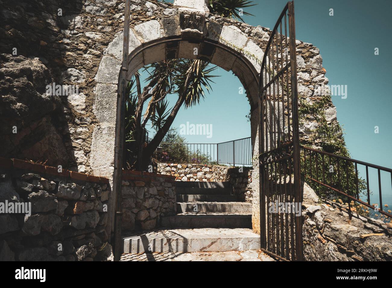 Old, vintage aged stone wall with arched opening gate and stairs up ...