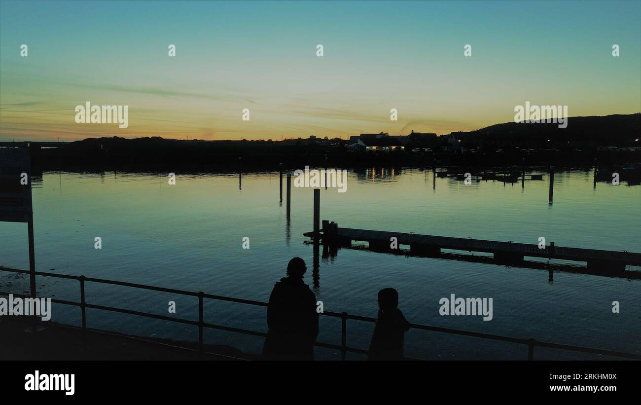 A group of people gathered on a dock at sunset, enjoying the ...