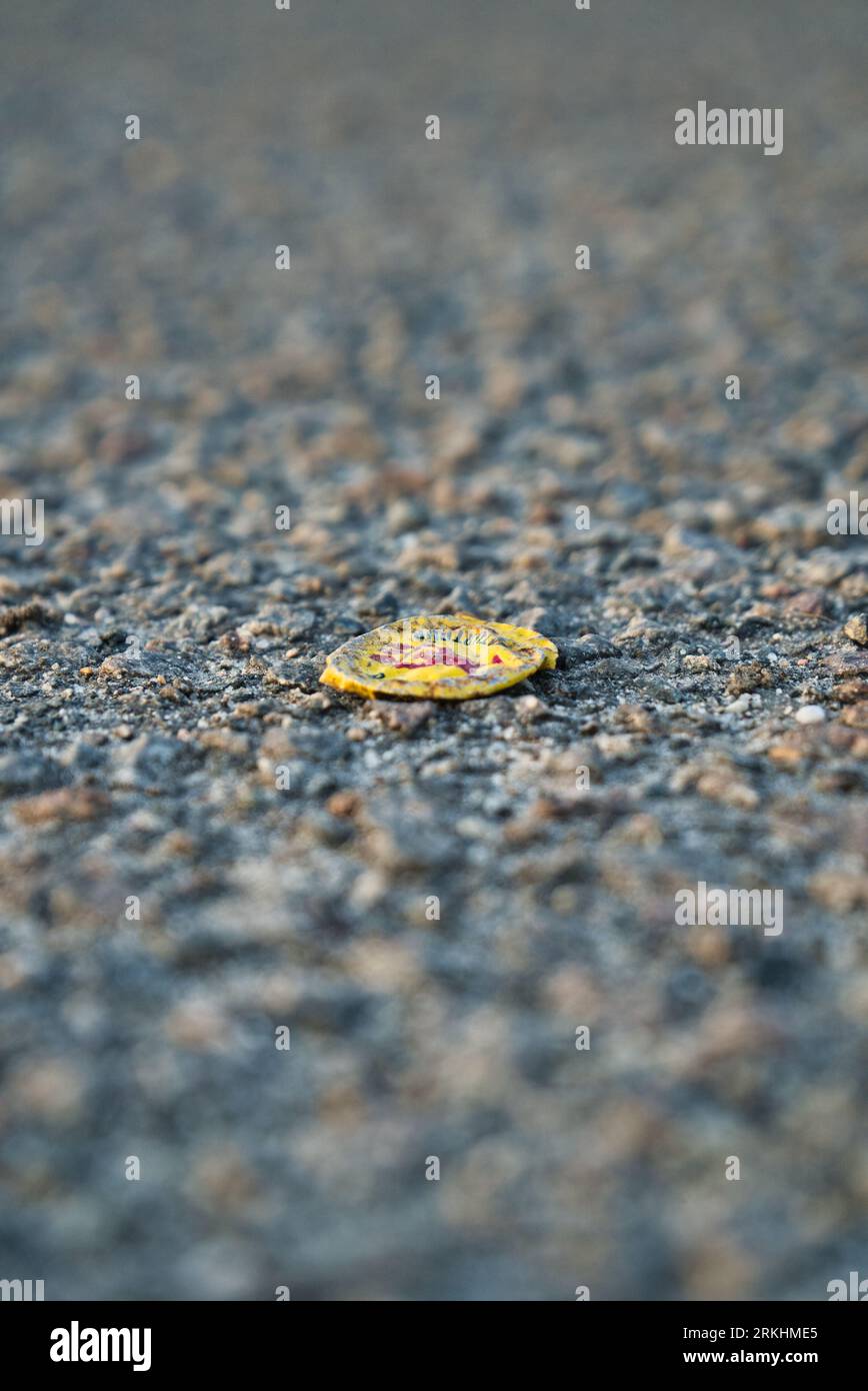 A close up of a small yellow object laying on the asphalt near a city ...