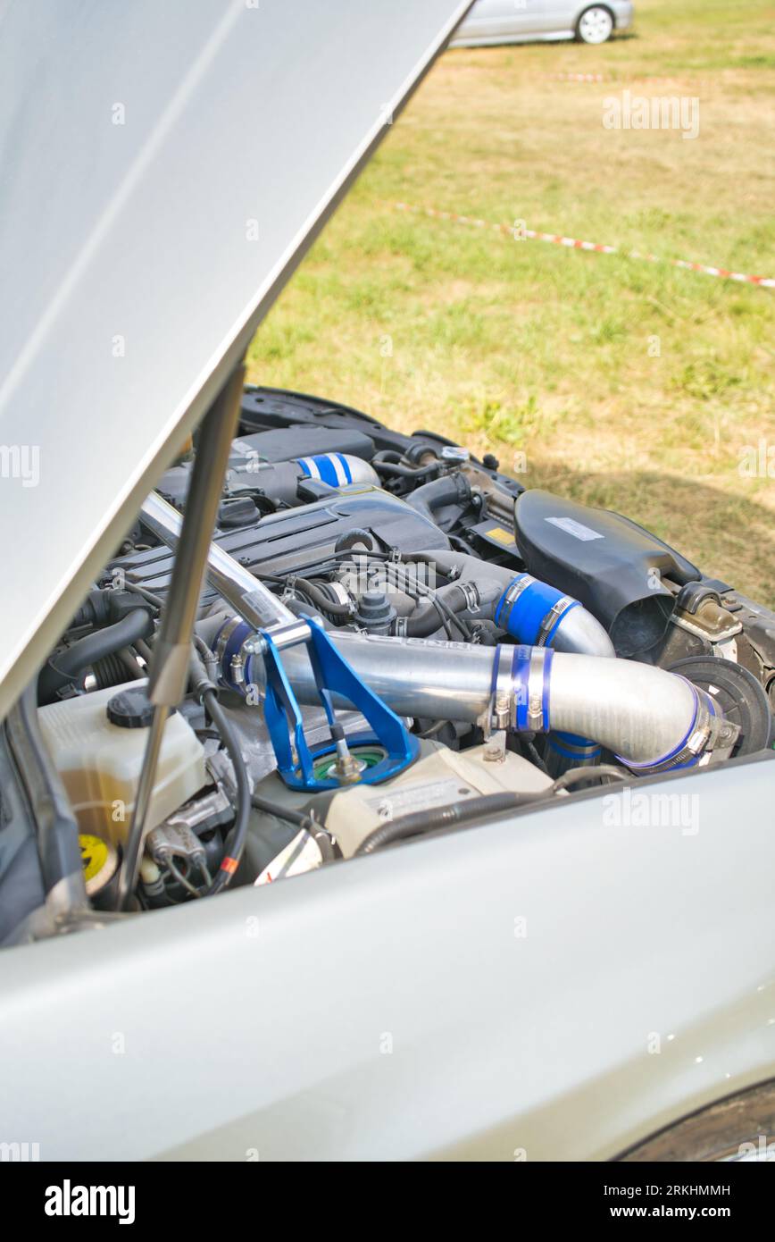 A close-up of an automobile engine compartment, with blue hoses and ...