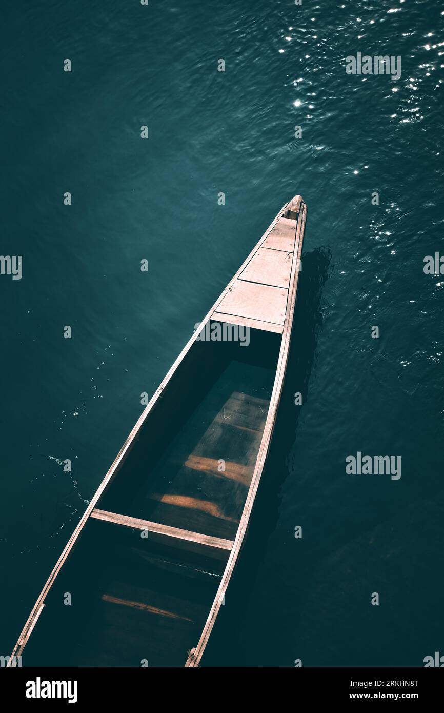 A vertical high angle shot of a wooden canoe floating in a large body ...