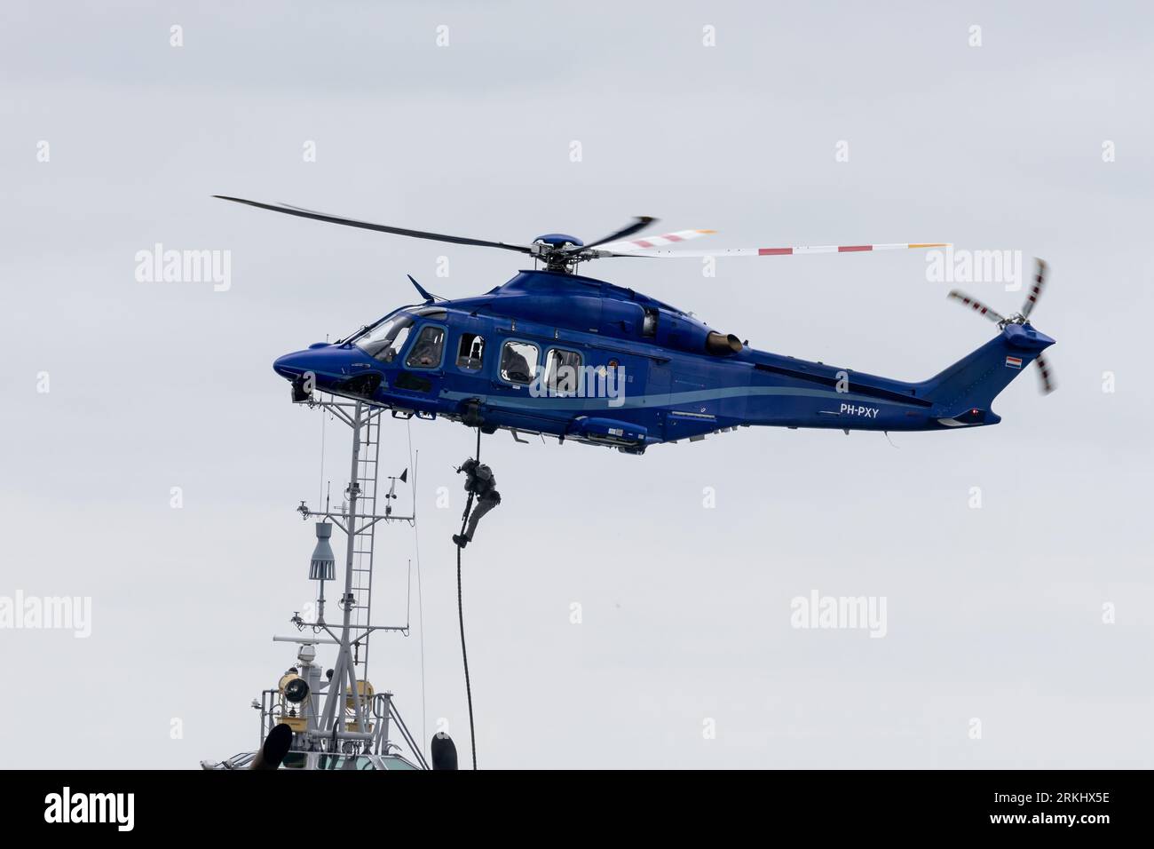 A helicopter hovering over a tug boat in the middle of an expansive ...