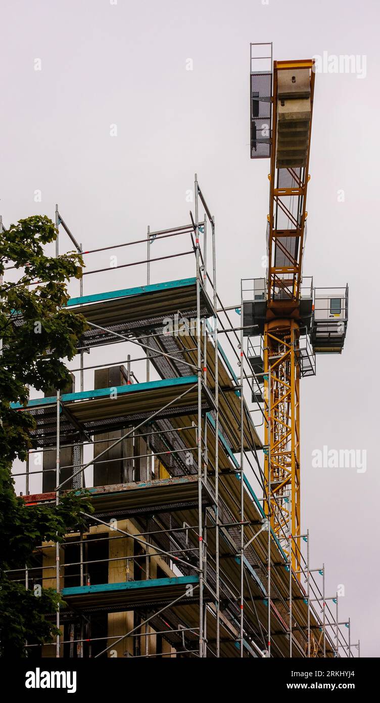A tall yellow tower crane positioned atop a large construction building ...