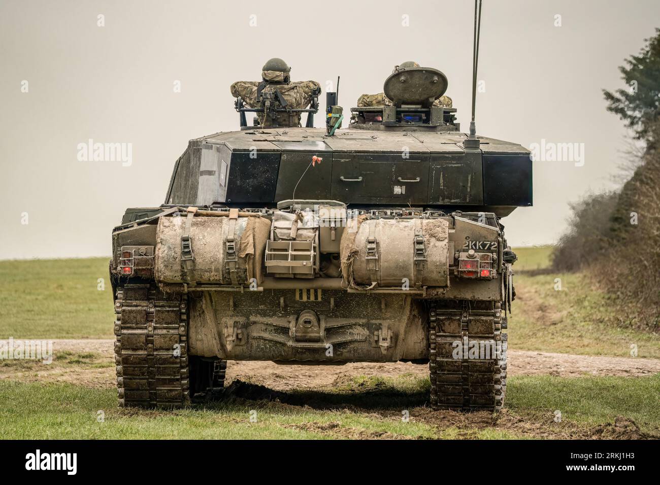 Two military personnel are seated on the roof of a heavily armored ...