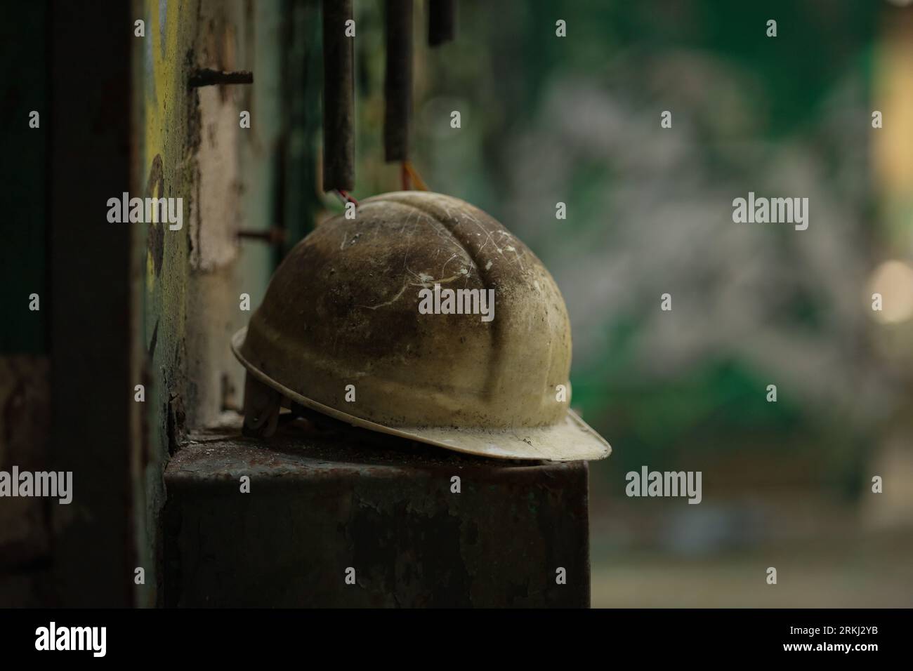 An aged, grimy hard hat resting on a ledge in an abandoned environment ...