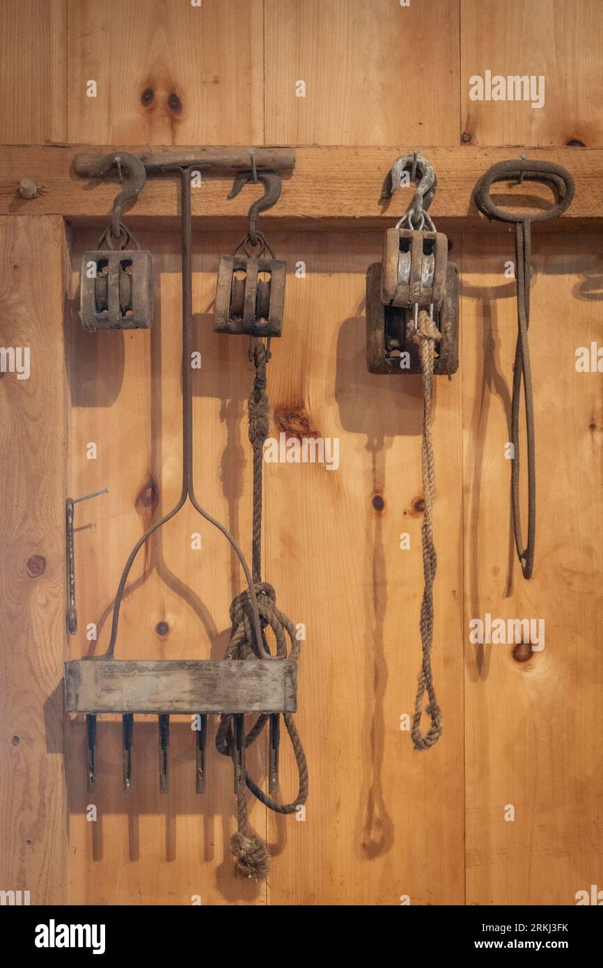 A collection of farm tools and shovels hung on the wall of a ...
