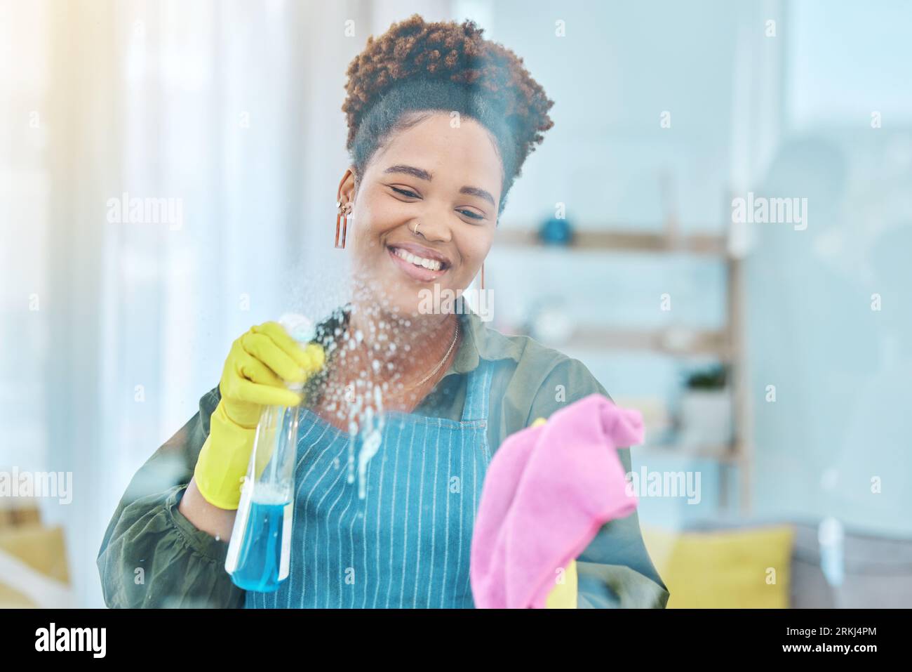 African woman, cleaning window with chemical spray and cloth, smile for ...