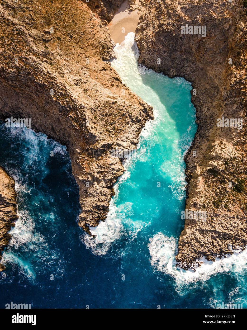An aerial view of ocean waves crashing against rocky cliffs of Crete ...