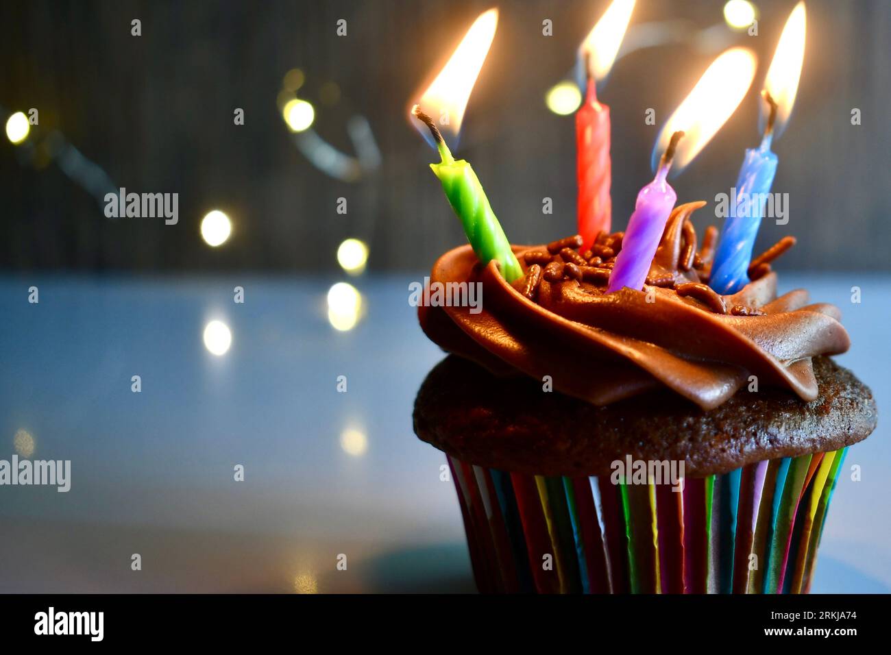 Chocolate cupcake with four colorful lit birthday candles Stock Photo ...
