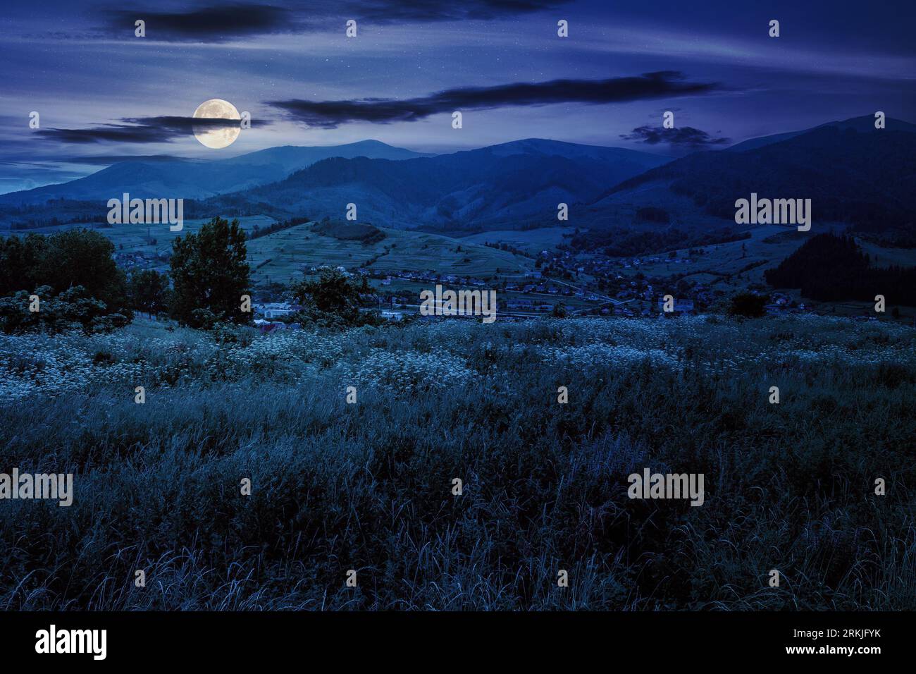 carpathian summer landscape at night. village in the valley. forest on ...