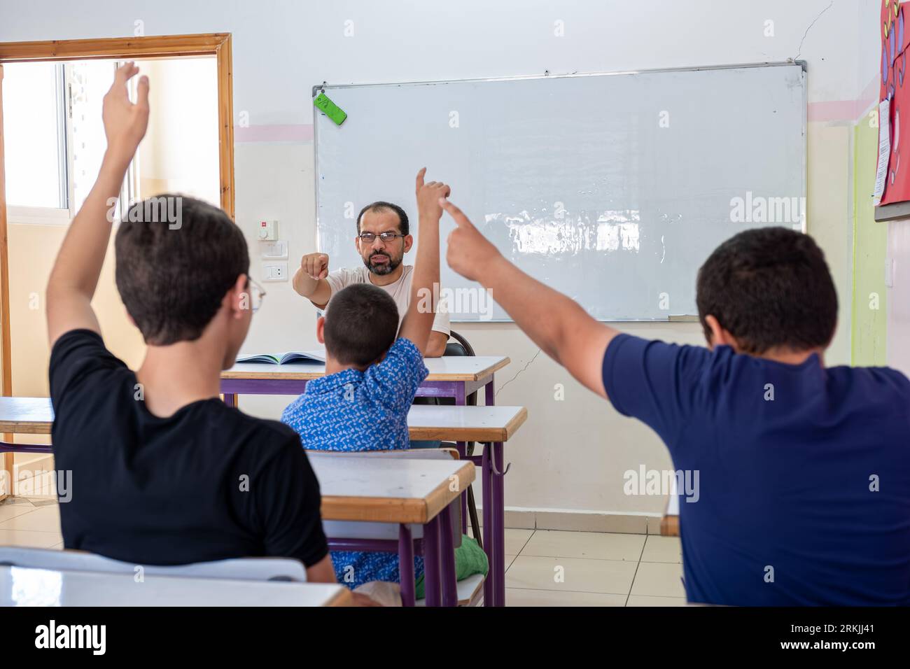 Students raising their hands to answer the teacher question Stock Photo ...