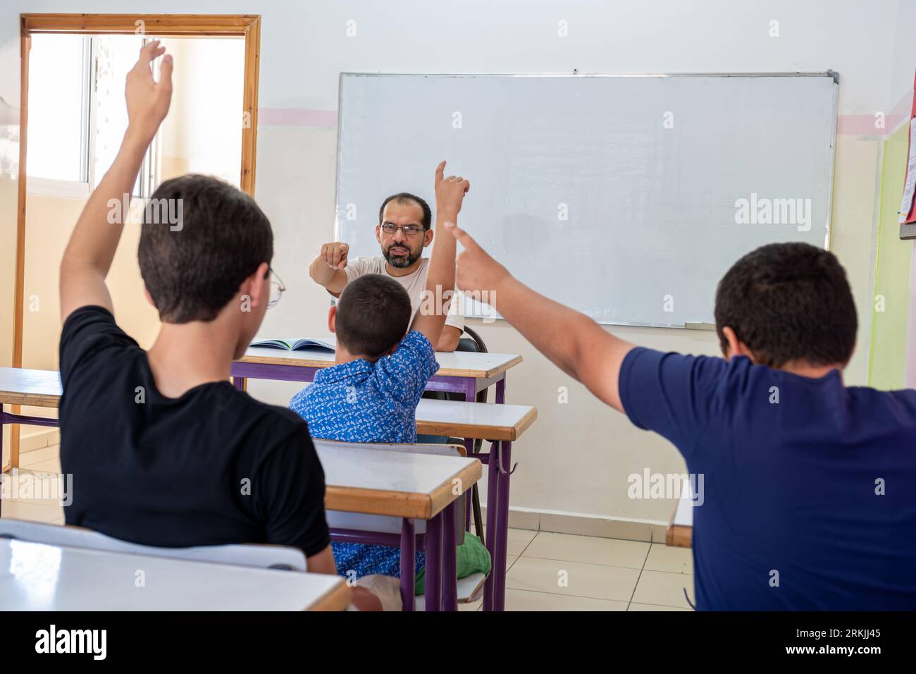 Students raising their hands to answer the teacher question Stock Photo ...