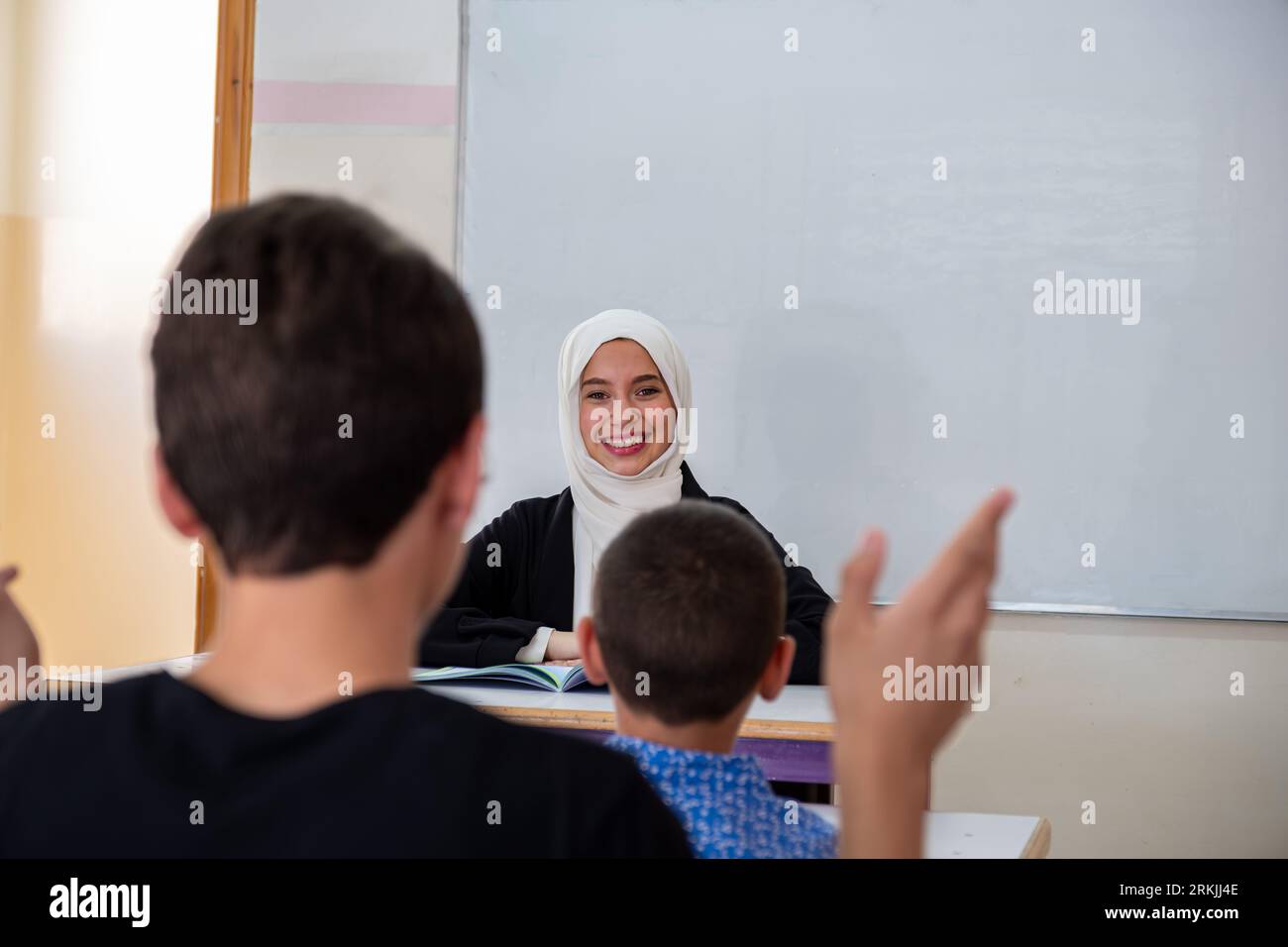 Students raising their hands to answer the teacher question Stock Photo - Alamy