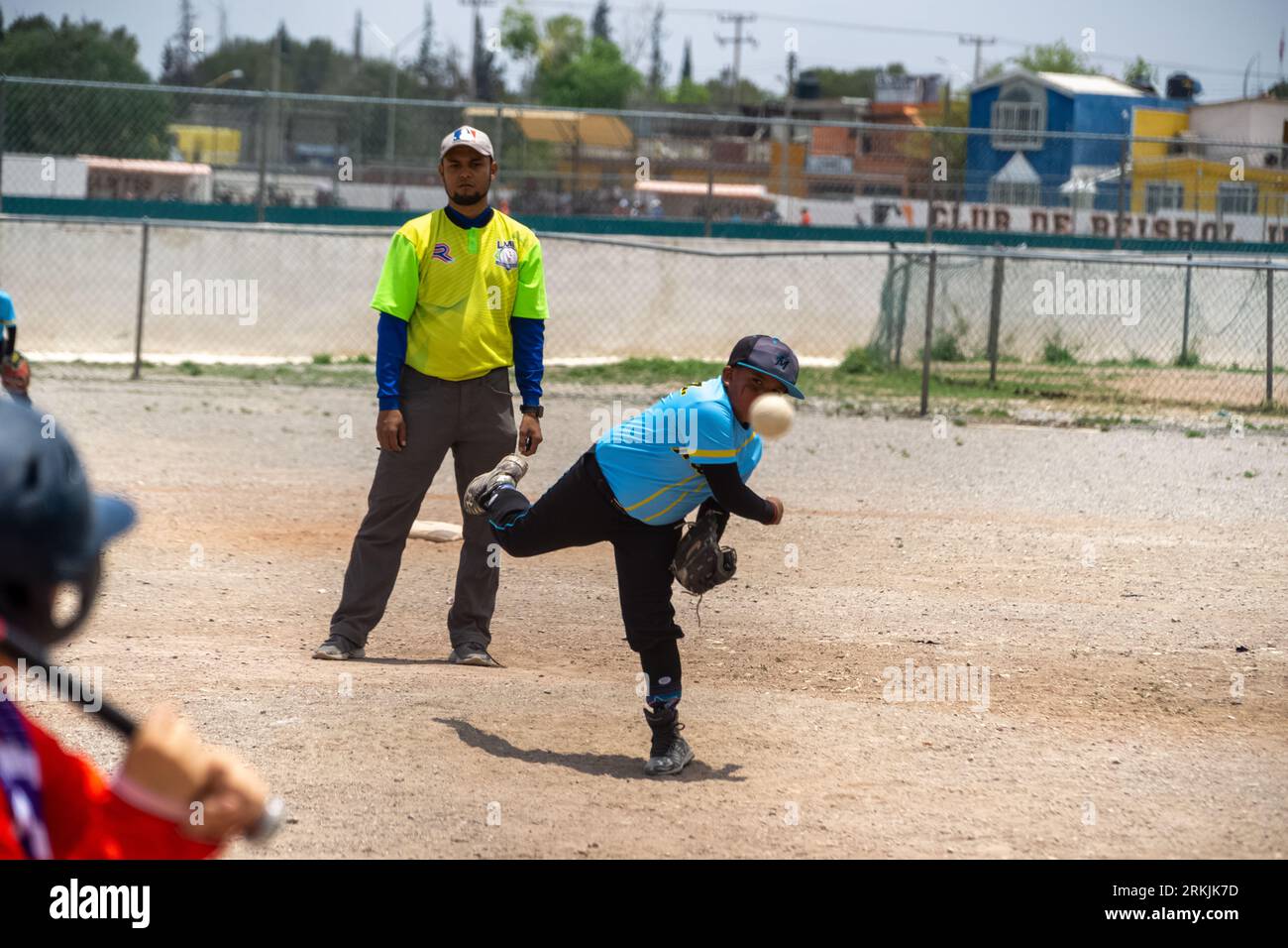 A young boy, wearing a baseball cap and blue uniform throwing a ball ...