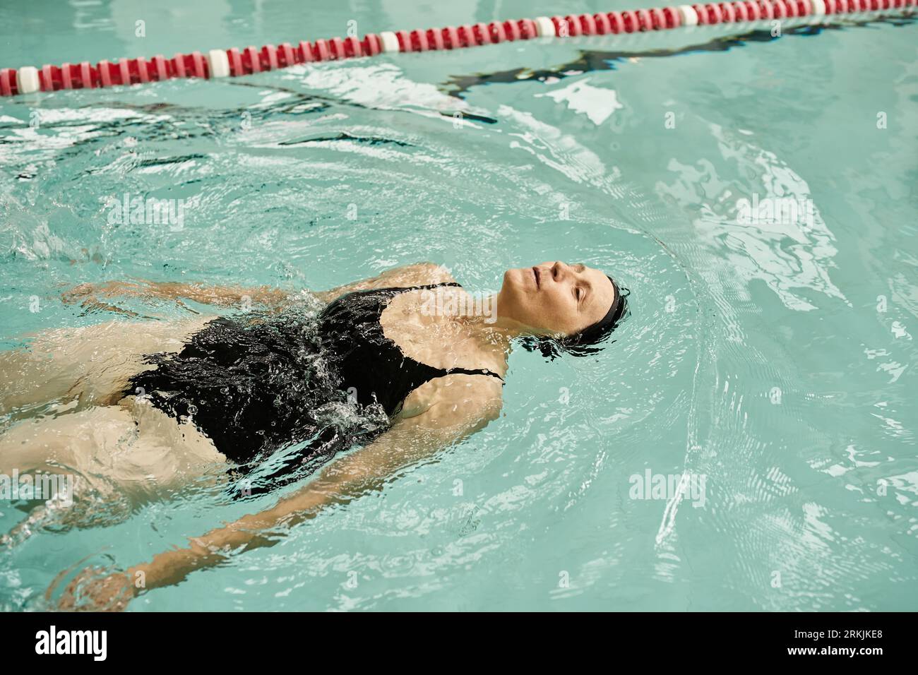 serenity, middle aged woman swimming on back in pool, swim cap and ...