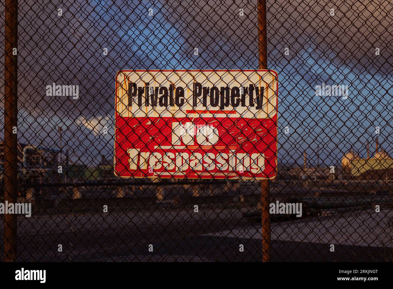 An industrial zone is protected by a chain-link fence with a warning ...