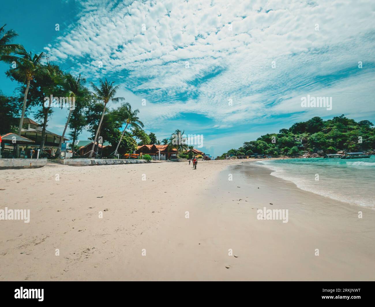 A group of people on a sandy beach, enjoy the bright blue sky above ...