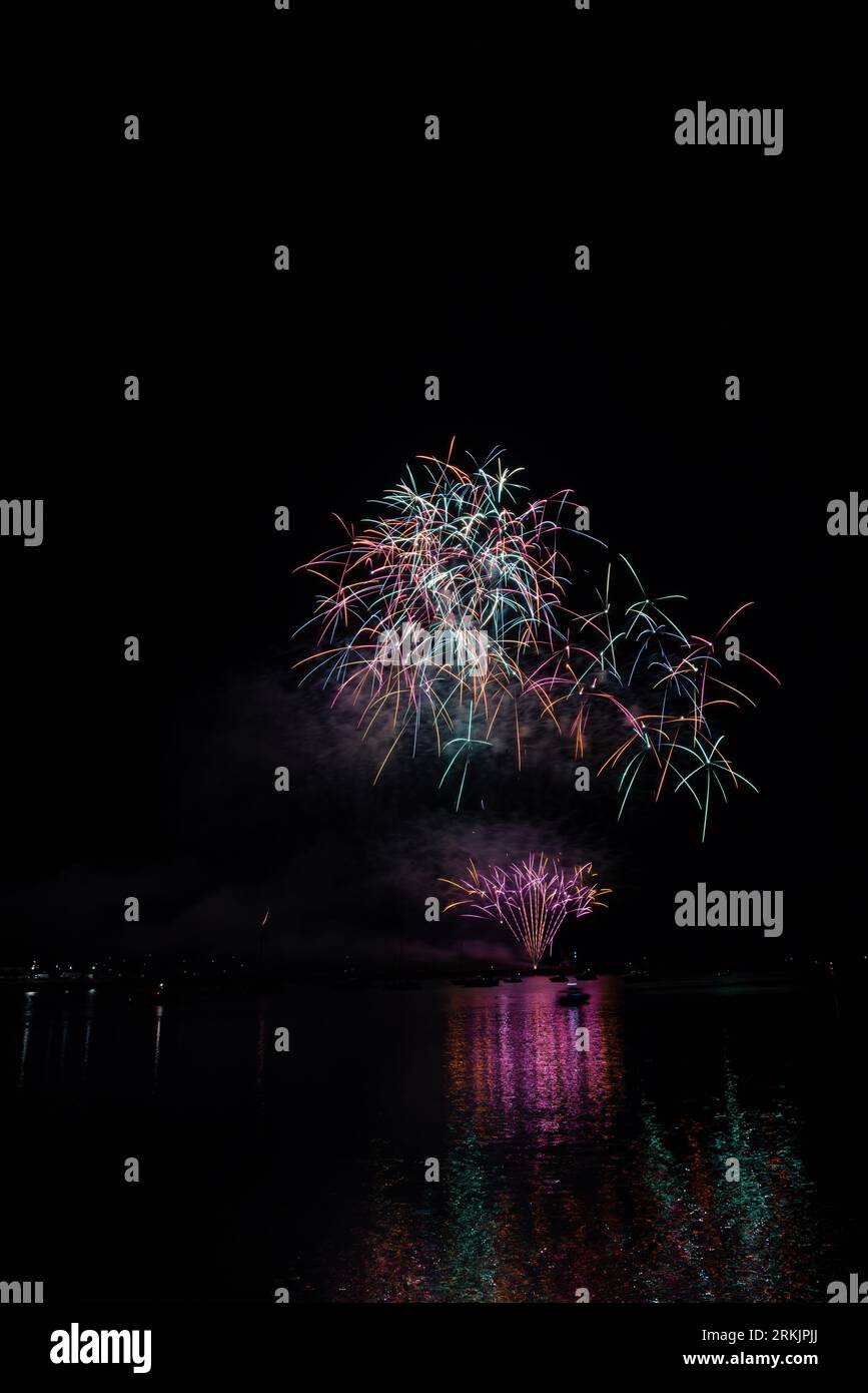 An aerial view of a lake inhabited by vibrant fireworks bursting in the ...