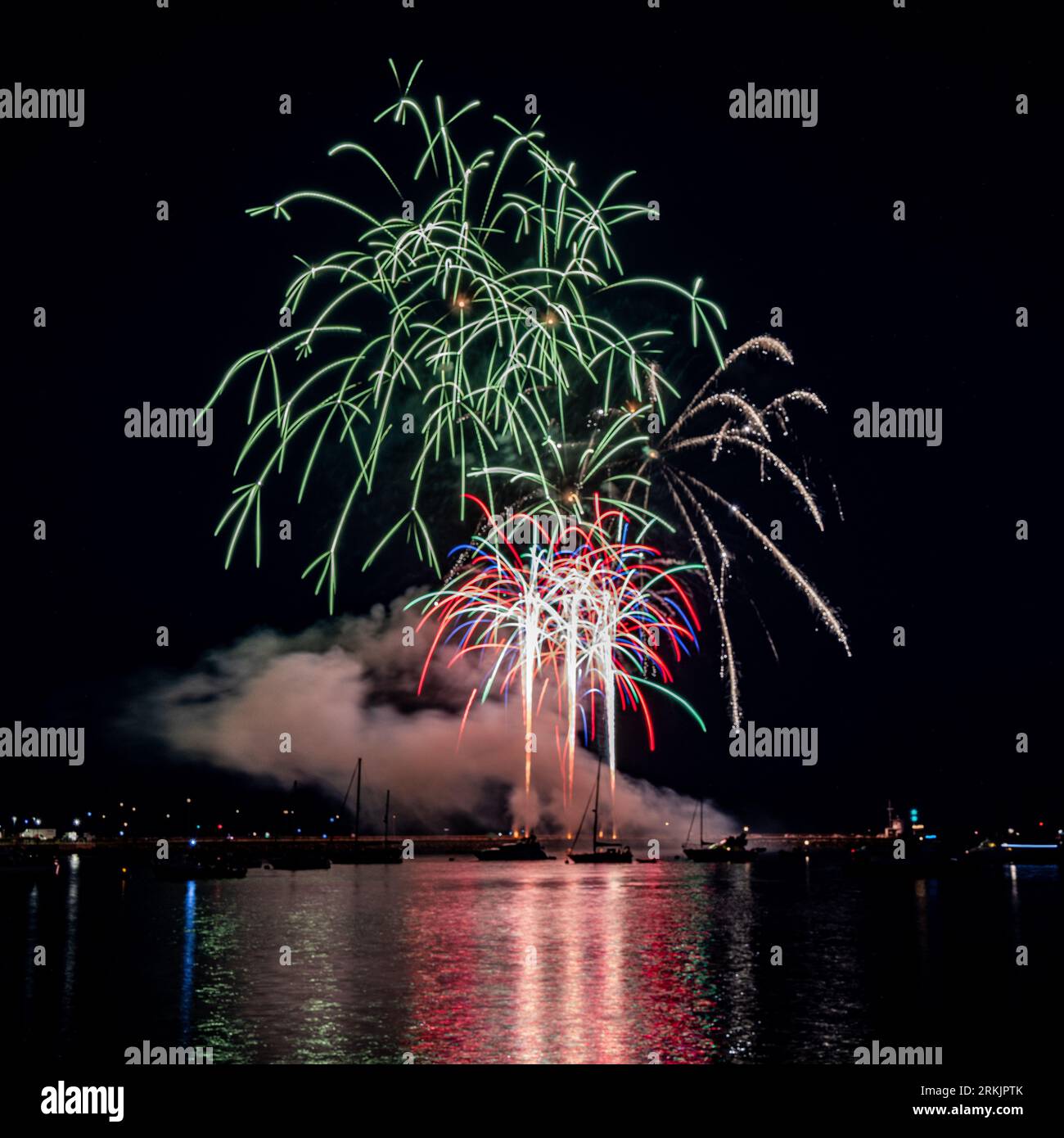 An aerial view of a lake inhabited by vibrant fireworks bursting in the ...