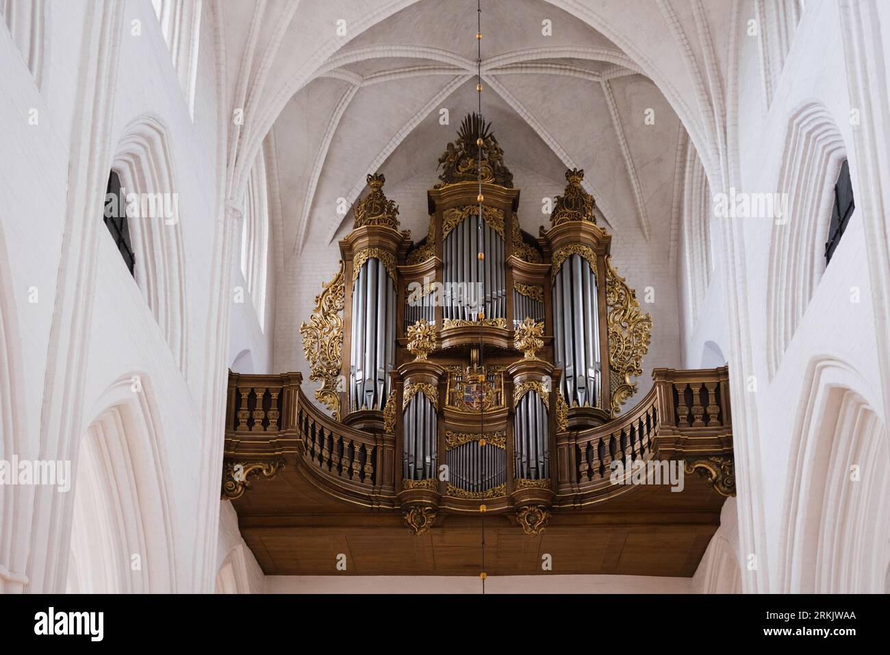Interior of a simple cathedral, white corridors and dark wooden pews ...