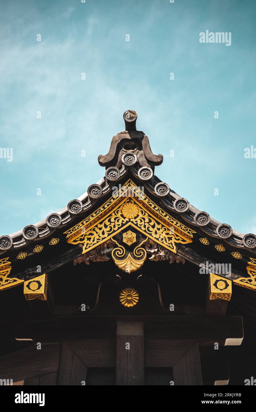 A traditional Japanese ornate wooden roof overhang with gold decoration ...