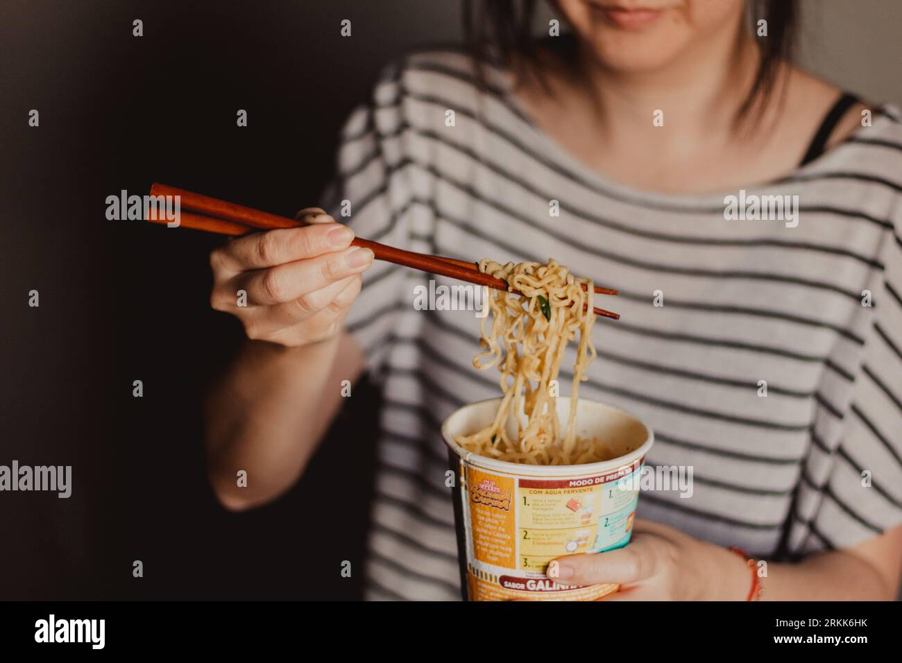 young woman eating instant noodles Stock Photo - Alamy