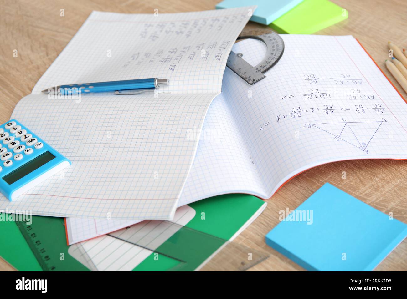 Open copybook with math formulas and stationery on wooden table ...