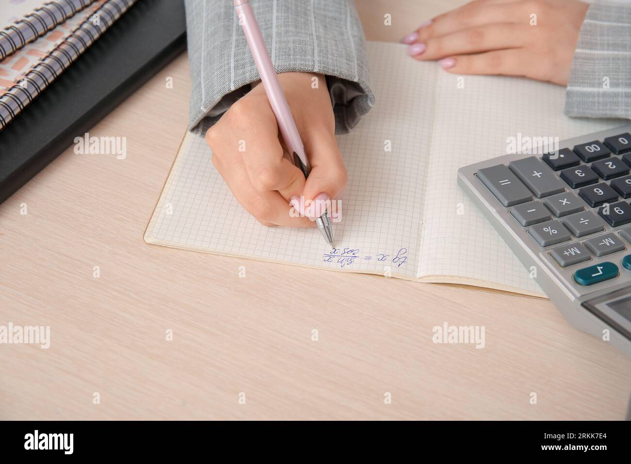 Female math teacher checking pupil's homework at wooden table, closeup ...