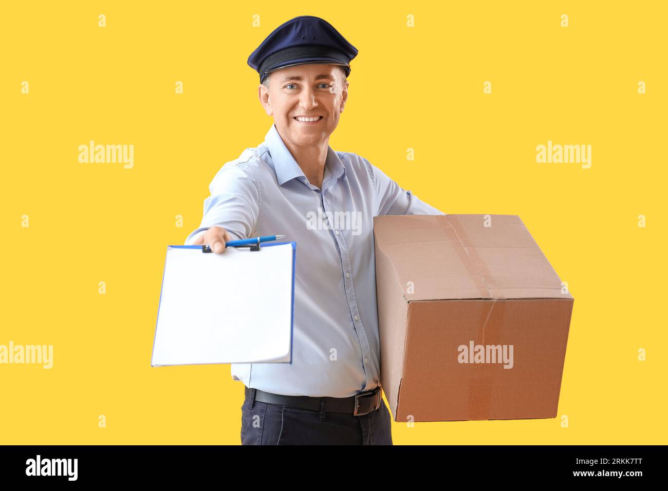 Mature postman with clipboard and parcel on yellow background Stock ...