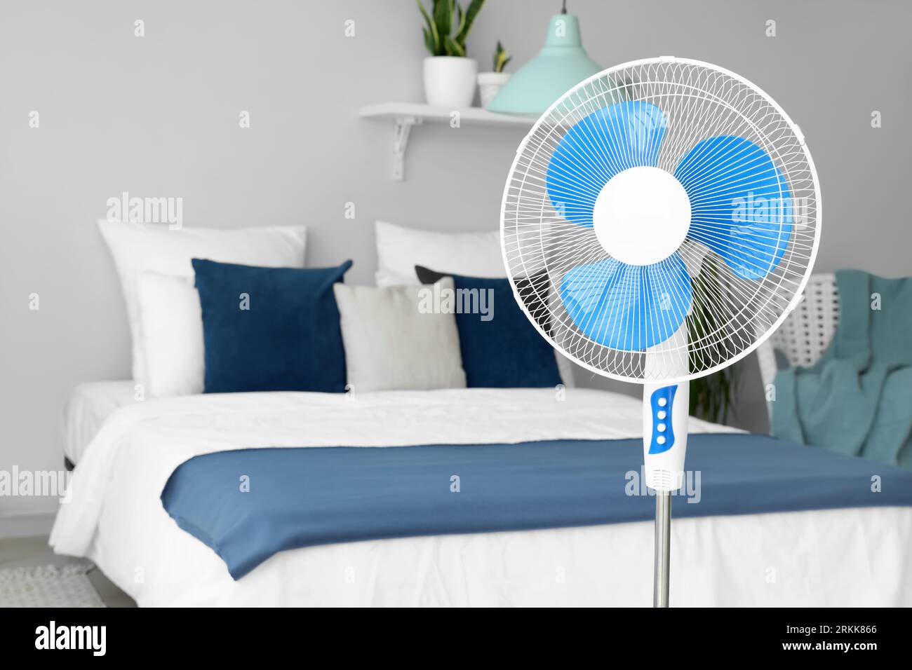 Floor fan and cozy bed in interior of light bedroom Stock Photo - Alamy