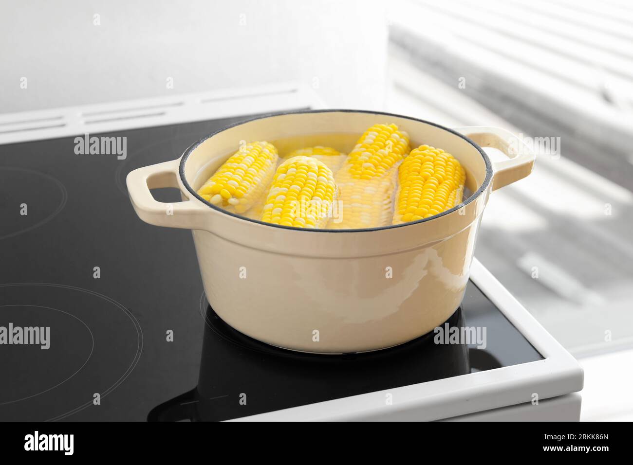 Cooking pot with boiling corn cobs on electric stove in kitchen Stock ...