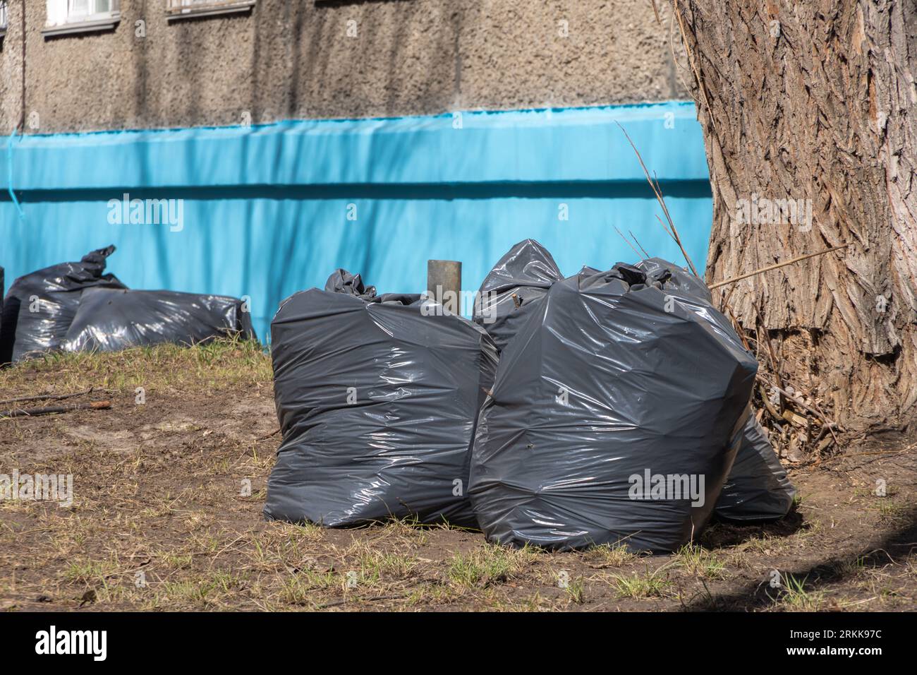 Pile of plastic garbage bags on the roadside near the city building ...