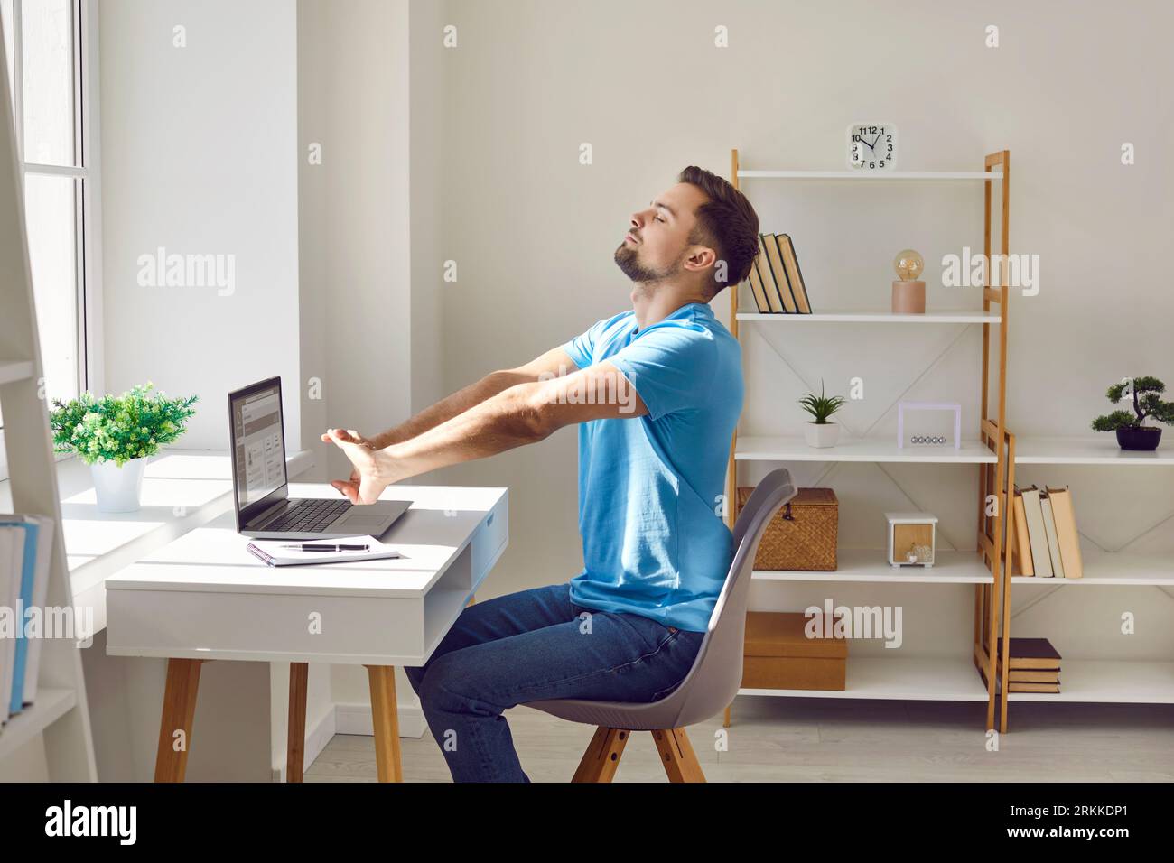 Relaxed tired business man resting and stretching arms at the desk ...