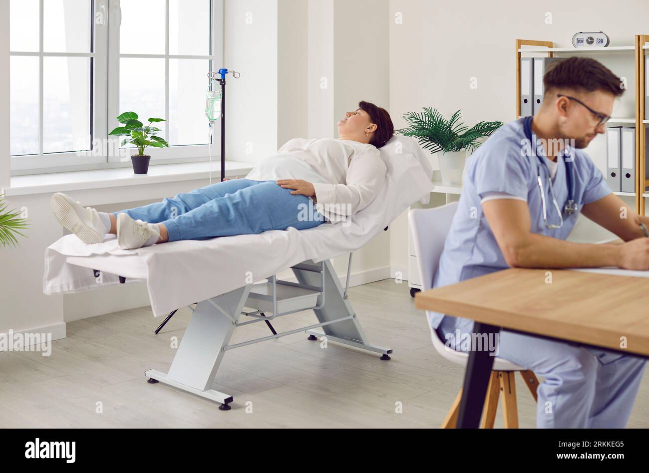 Sick overweight woman lying in clinic and receiving IV drip infusion ...