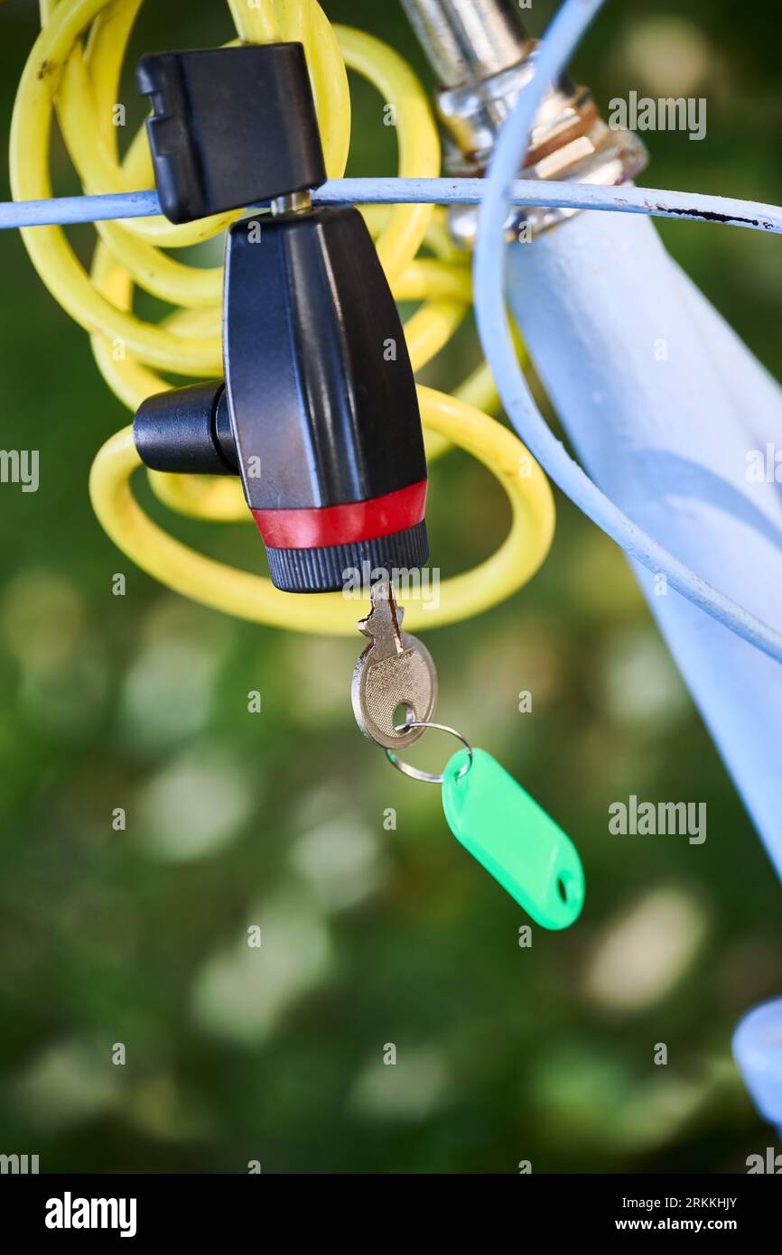 Anti-theft chain lock with yellow cable securing a white bicycle Stock ...