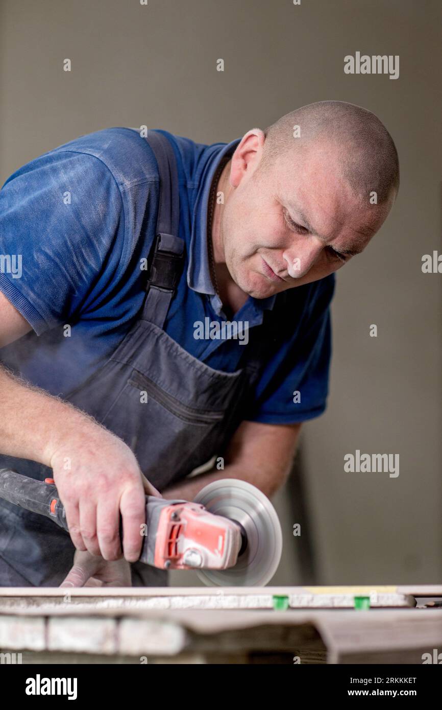 Professional tiler cutting tile with angle grinder. Construction ...