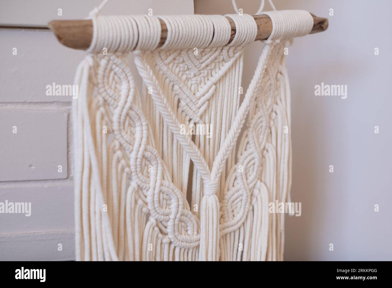 White macrame decor on wooden stem. Handicrafts poster. Copy space ...
