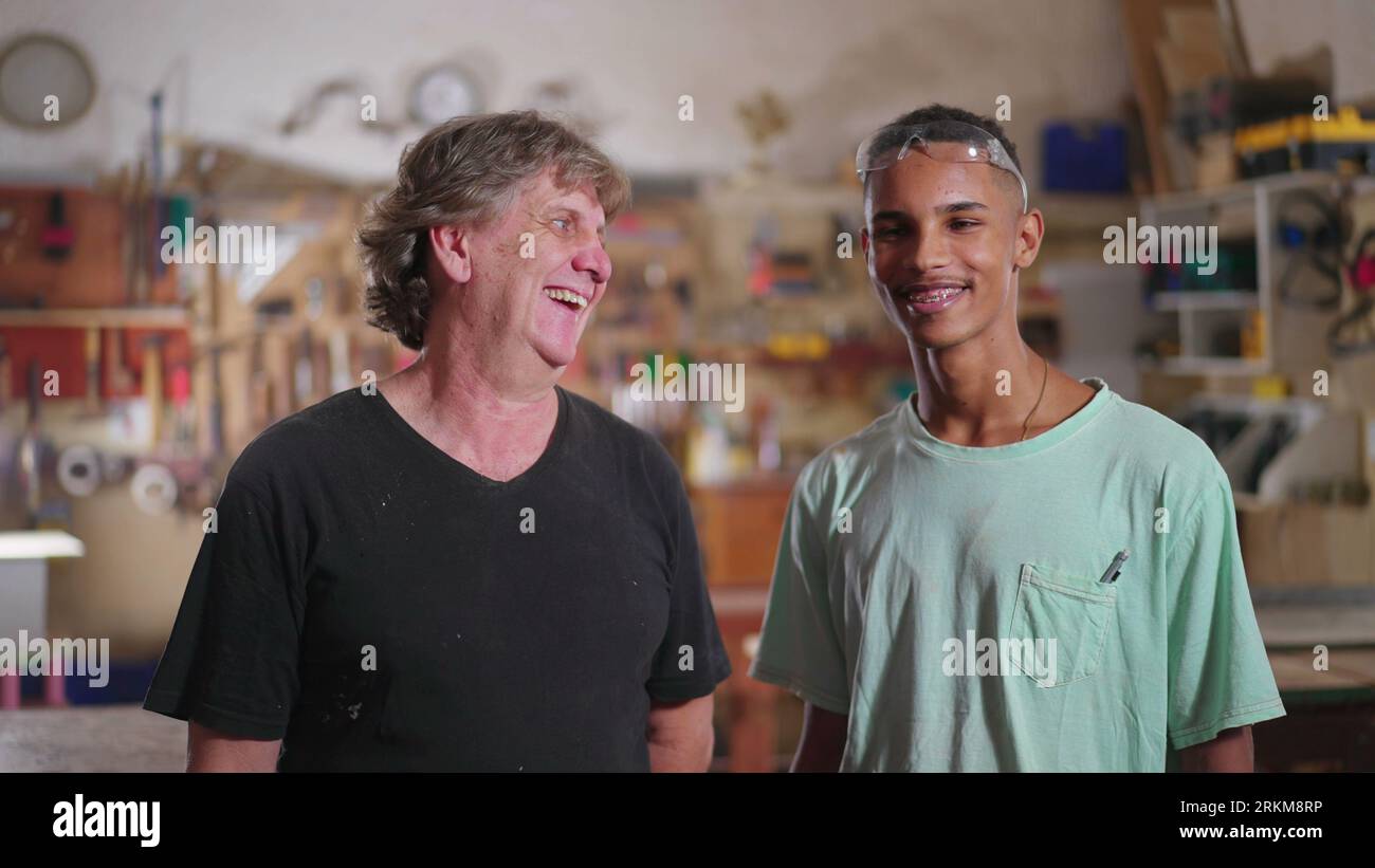 Portrait of senior carpenter goofing around with younger apprentice ...