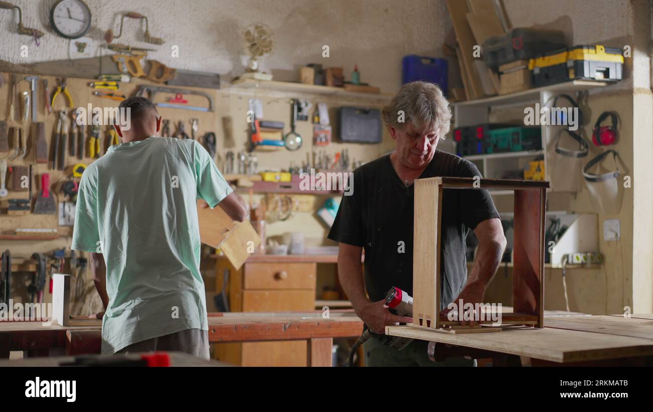Carpentry shop scene of two carpenters working with tools to build and ...