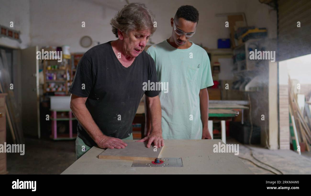 Master carpenter orienting apprentice to work with machine at ...
