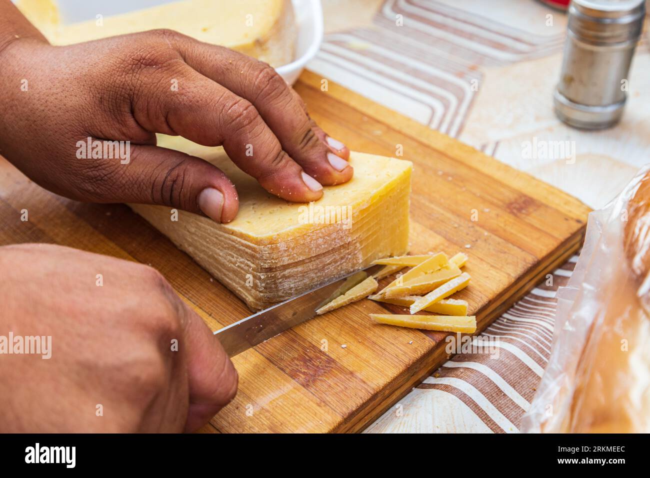 Cairo, Egypt, Africa. Trimming the rind off a block of rumi cheese ...