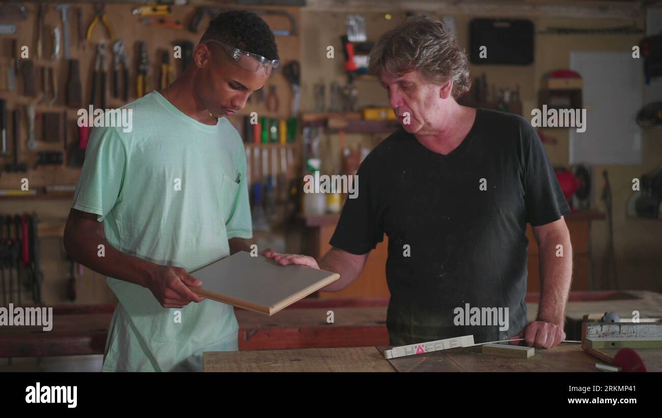 Senior master carpenter orienting apprentice at carpentry workshop ...