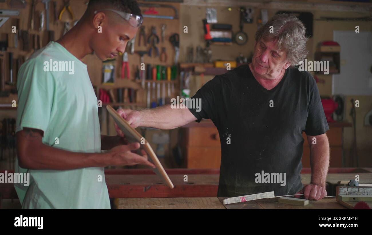 Senior master carpenter orienting apprentice at carpentry workshop ...